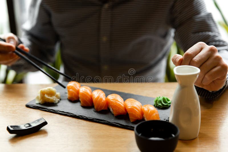 Man Salmon Sushi on Restaurant Table. Asian Man Eating Salmon Sushi Set ...