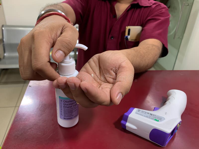 Man Sanitizing Hand and Checking Temperature with Digital Thermometer ...