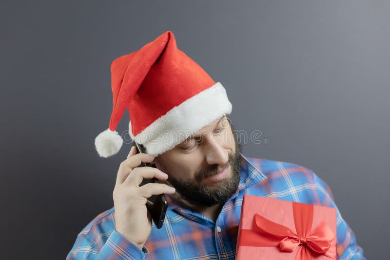 A Man in a Santa Hat with a Red Box with a Gift Talking on a Cell Phone ...