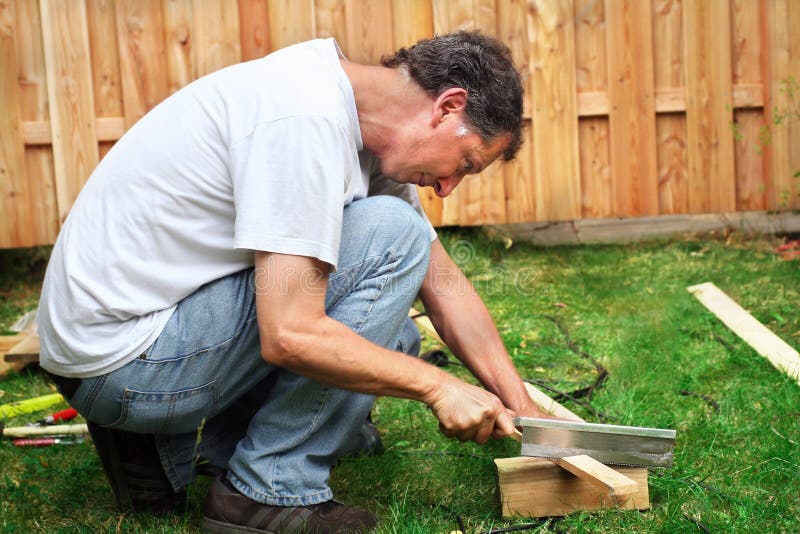 Man sawing a piece of wood stock photo. Image of crouching - 10165516