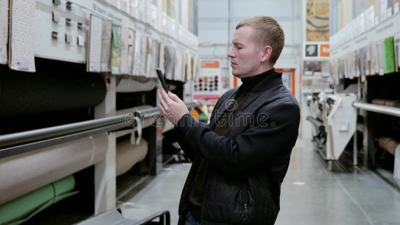 Man Using Smartphone Scanning Qr Code on a Roll of Carpet in a Hardware ...