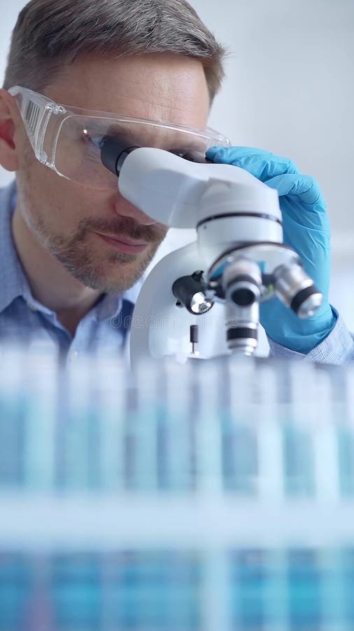 Man Scientist with Protective Glasses and Gloves is Using Microscope in ...