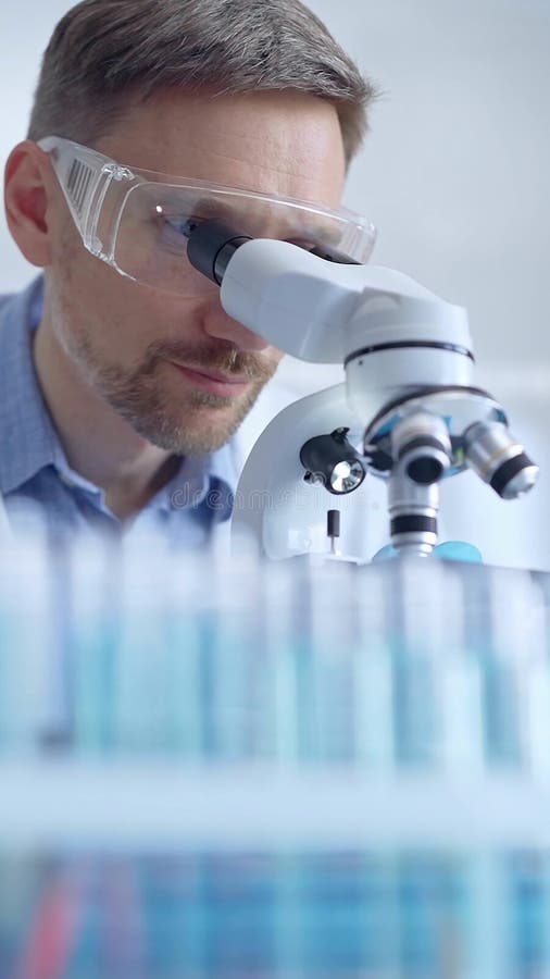 Man Scientist with Protective Glasses and Gloves is Using Microscope in ...