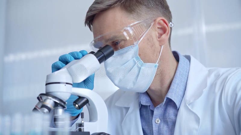 Man Scientist with Protective Glasses, Mask and Gloves is Using ...