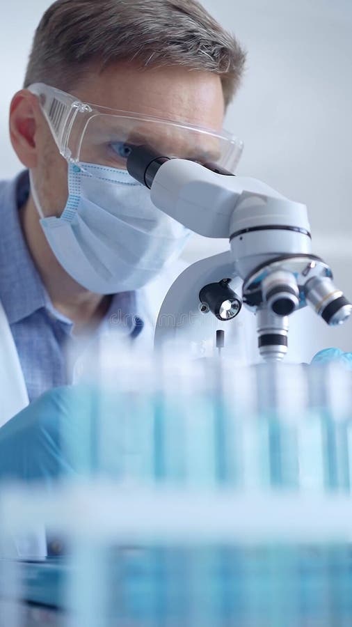Man Scientist with Protective Glasses, Mask and Gloves is Using ...