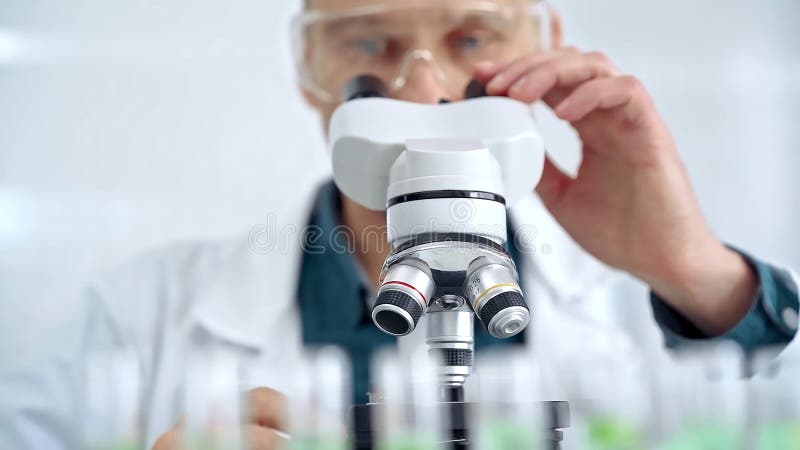 Man Scientist with Protective Glasses Using Microscope in Laboratory ...