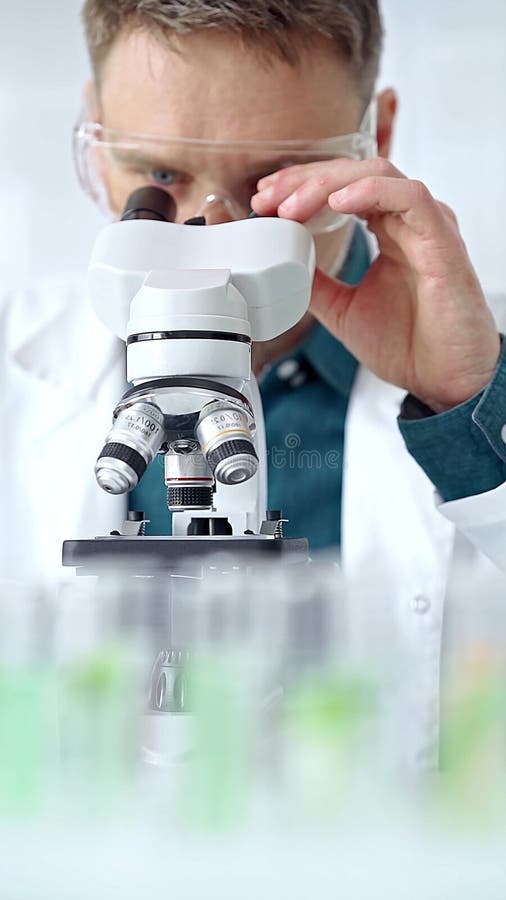 Man Scientist with Protective Glasses Using Microscope in Laboratory ...