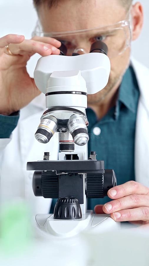 Man Scientist with Protective Glasses Using Microscope in Laboratory ...