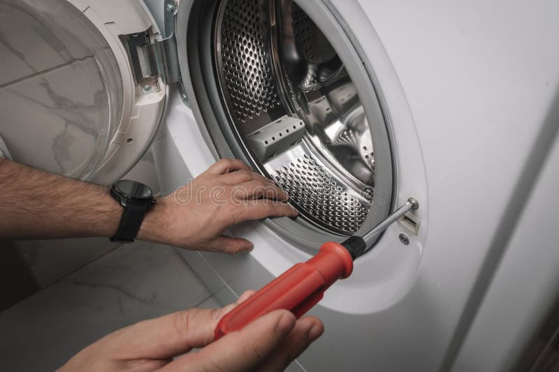 A Man with a Screwdriver Disassembles a Washing Machine. Technician ...
