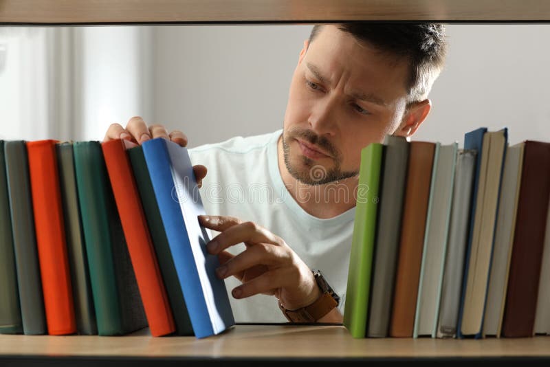 Man Searching for Book on Shelf in Library Stock Image - Image of ...