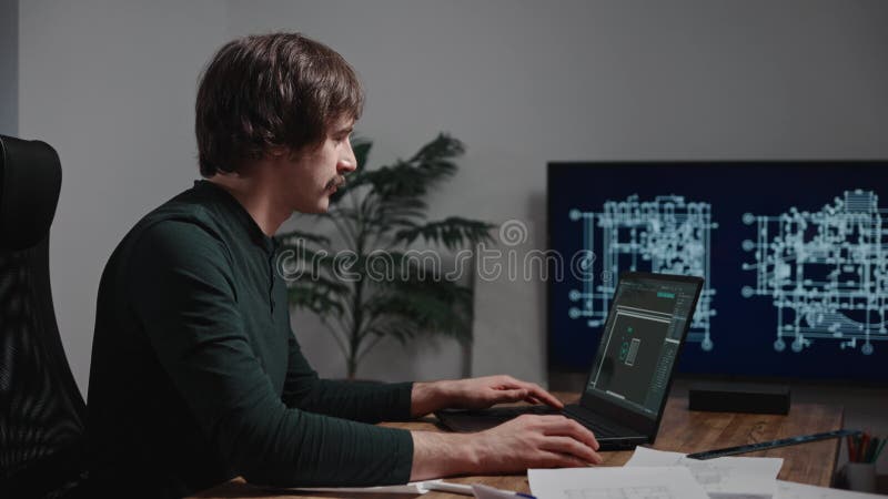 A Man is Seated at a Desk Using a Laptop Computer As an Output Device ...