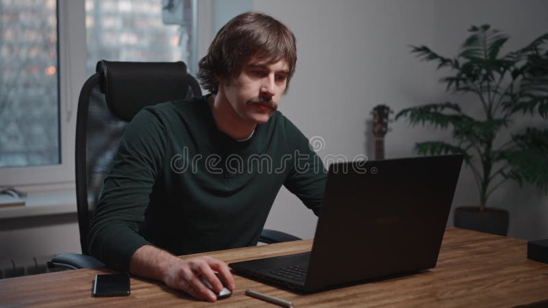Man Seated at Table, Using Laptop Computer in Office Setting Stock ...