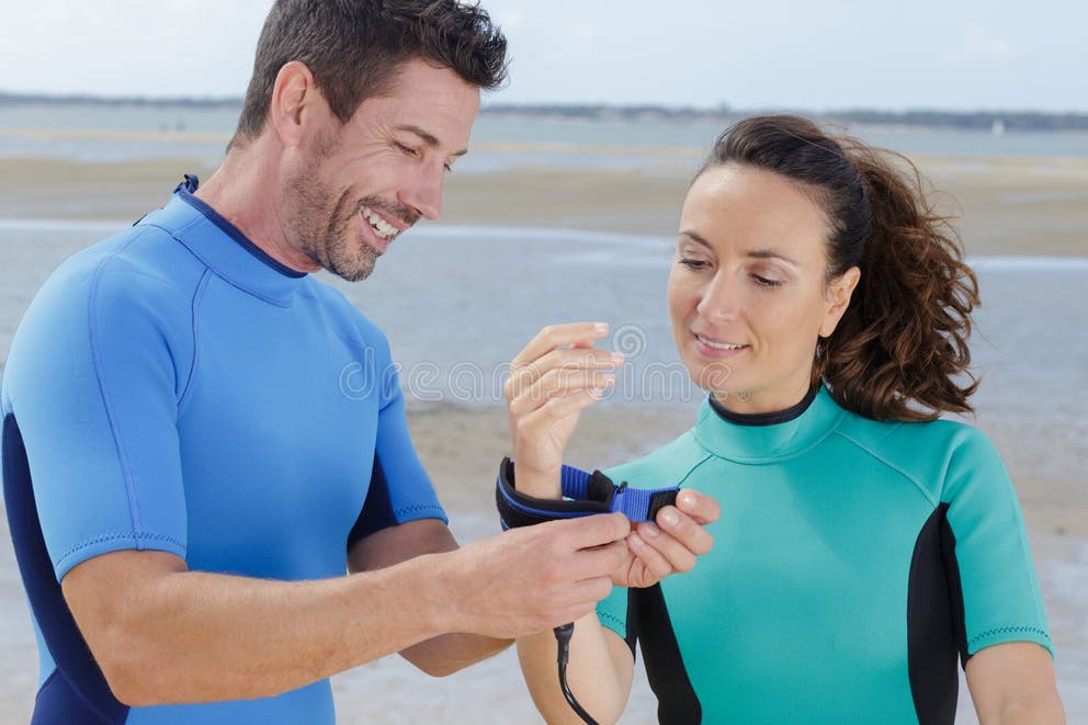 Man Securing Womans Wrist Strap before Surfing Stock Image - Image of ...