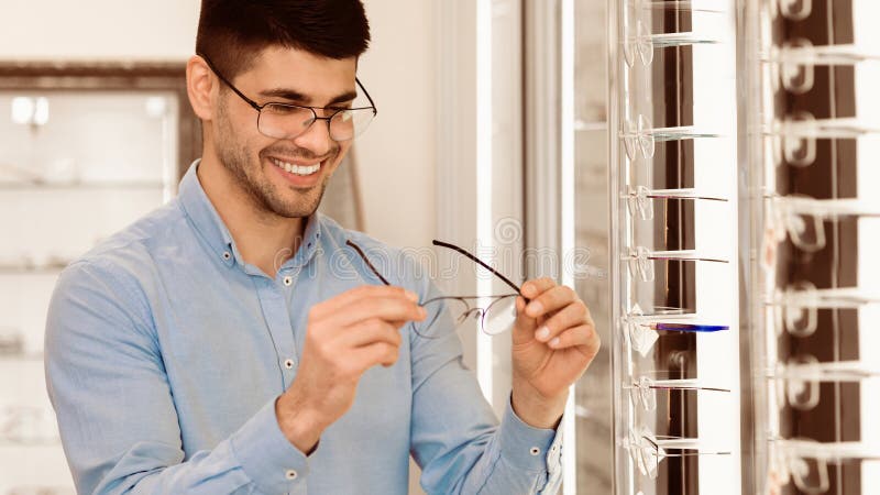 Man Selecting Stylish Eyeglasses in a Modern Optical Store Setting ...