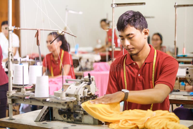 Seamstress In Textile Factory Smiling While Sewing With Industr Stock