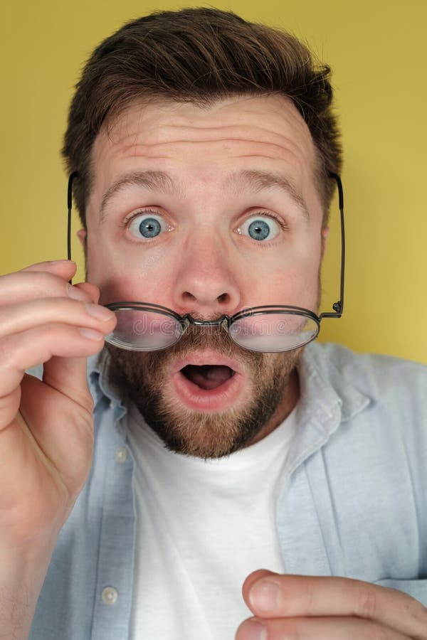Man With A Shocked Expression Holds His Glasses Which He Took Off In