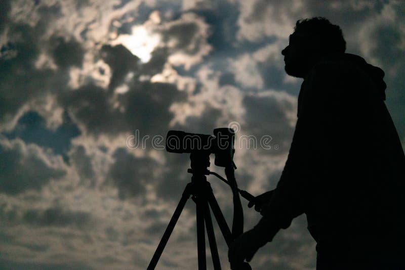 Man Shooting the Night Cloudy Sky Under Moon with a Tripod Stock Photo ...