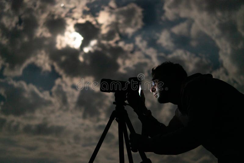 Man Shooting the Night Cloudy Sky Under Moon with a Tripod Stock Image ...