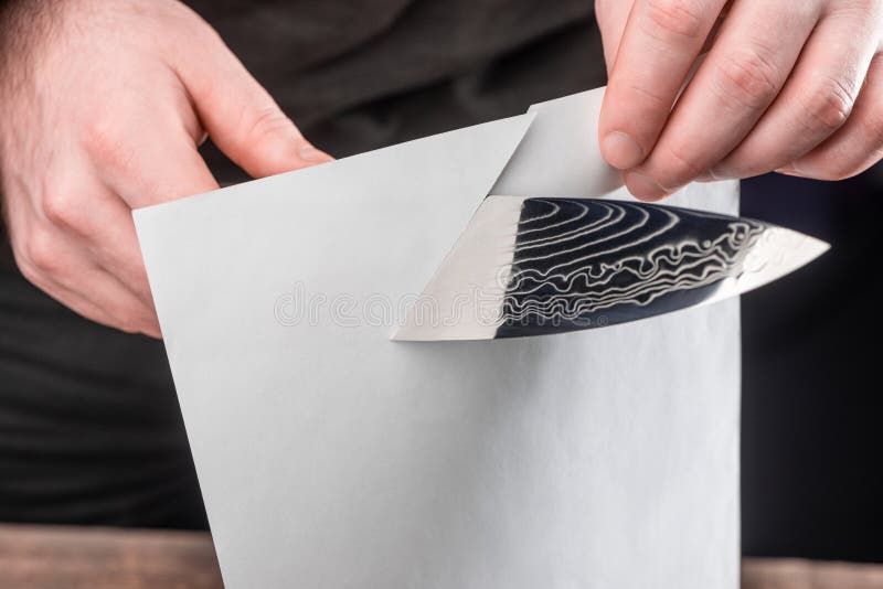 Man Showing Sharpness of a Knife by Cutting a Thin Paper Sheet Stock ...