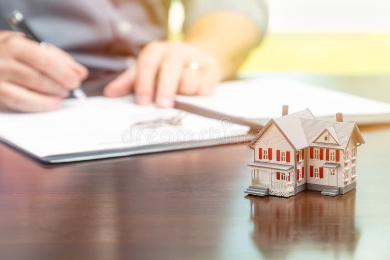 Man Signing Real Estate Contract Papers with Small Model Home in Front ...