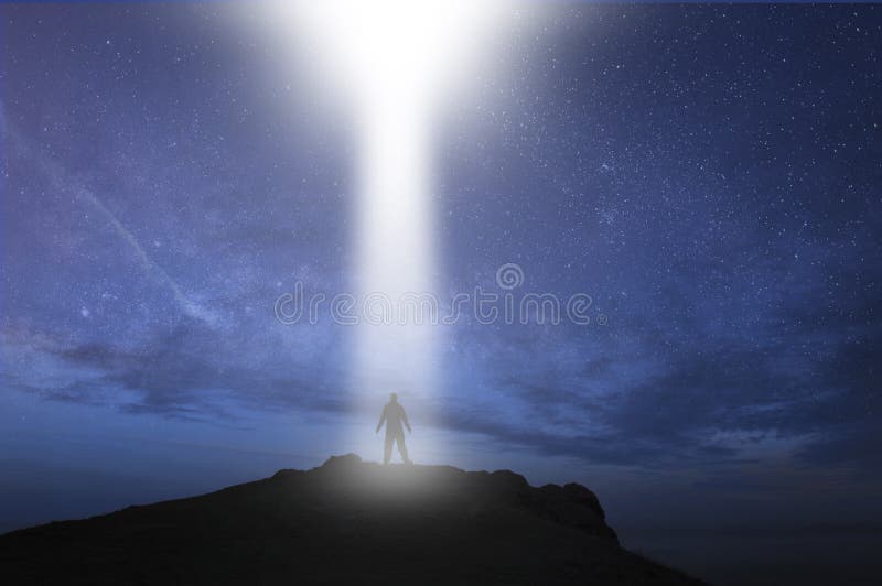 A Man Silhouetted, Standing on Top of a Hill with a UFO Light Beam ...
