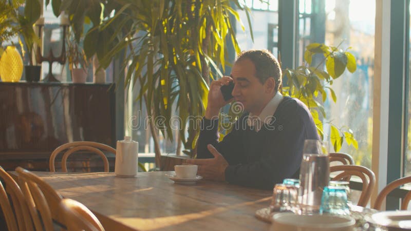 Man Sit at a Table in Cafe and Talk on Phone Stock Image - Image of ...