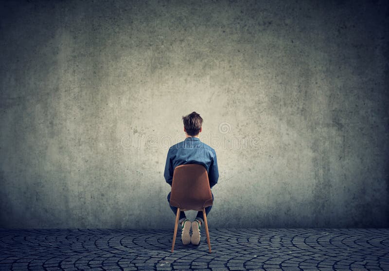 A Man Sits on a Chair and Looks at an Empty Concrete Wall Stock Image ...