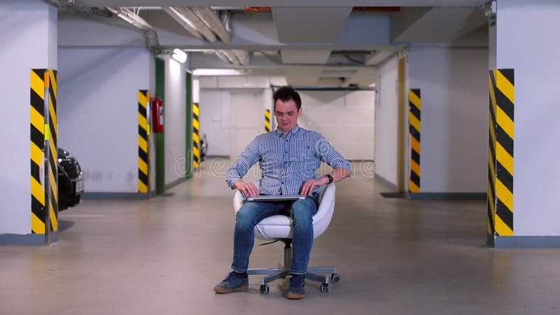 A Man Sits in a Chair in an Underground Garage. Stock Footage - Video ...