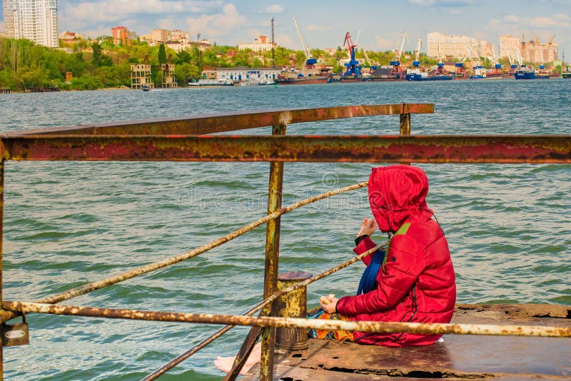 A Man Sits on the Dock and Throws Bread into the Water Stock Photo ...
