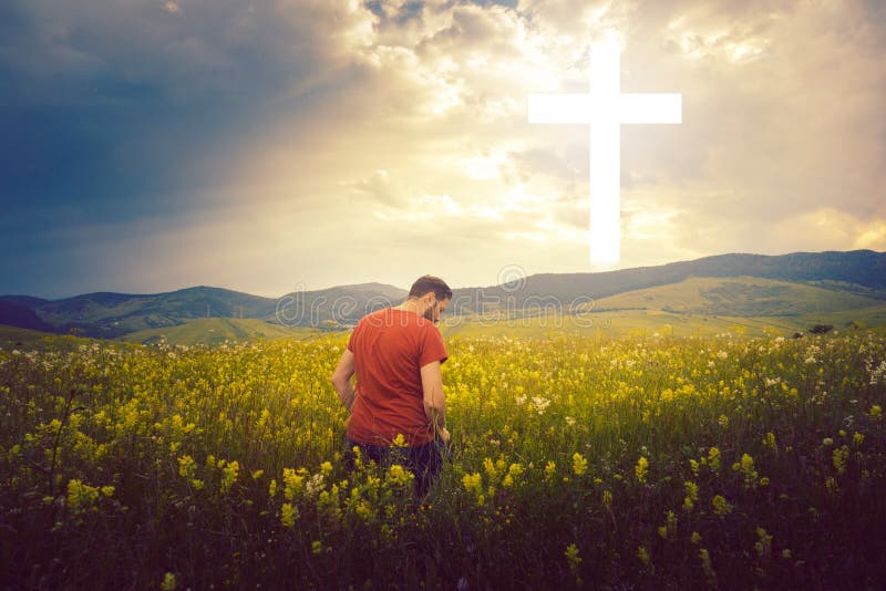 Man Sits in a Meadow Looking at a Cross of Light Like a Miracle Stock ...