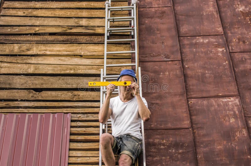 A Man Sits on the Roof on a Ladder with a Building Level Stock Image ...