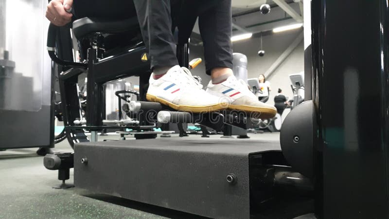 A Man Sits on a Simulator in a Gym and Does an Exercise on the Leg ...