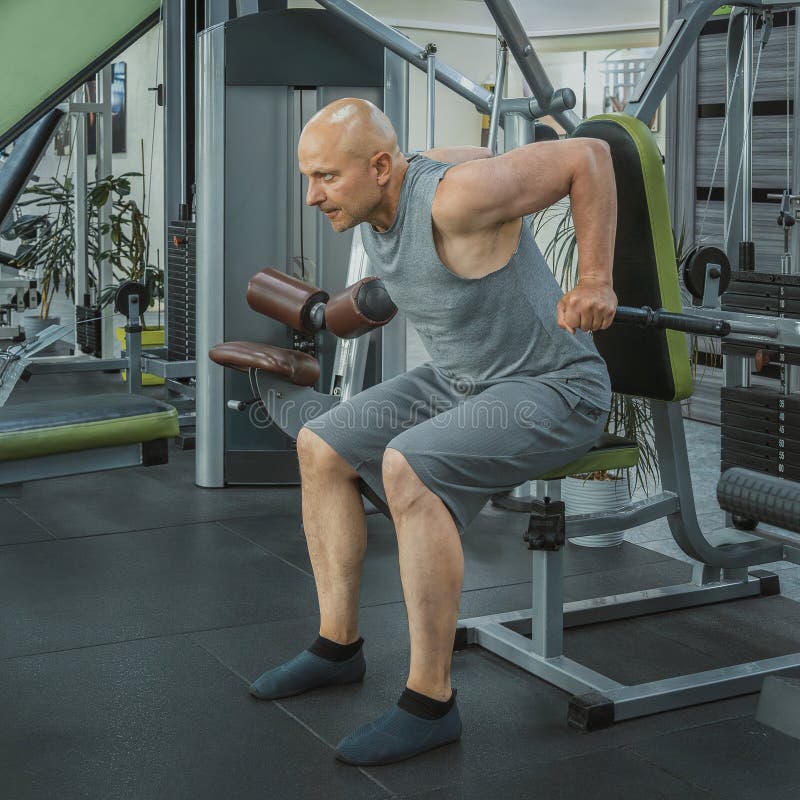 Man Sits in a Simulator and Performs an Exercise for Pumping Triceps ...