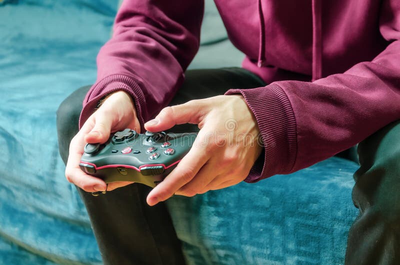 Man Sits on Sofa Holding Game Controller, Playing Remote Controlled ...