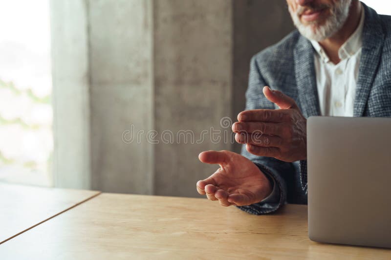 A Man Sits at a Table with a Laptop and Talks To Someone Stock Image ...