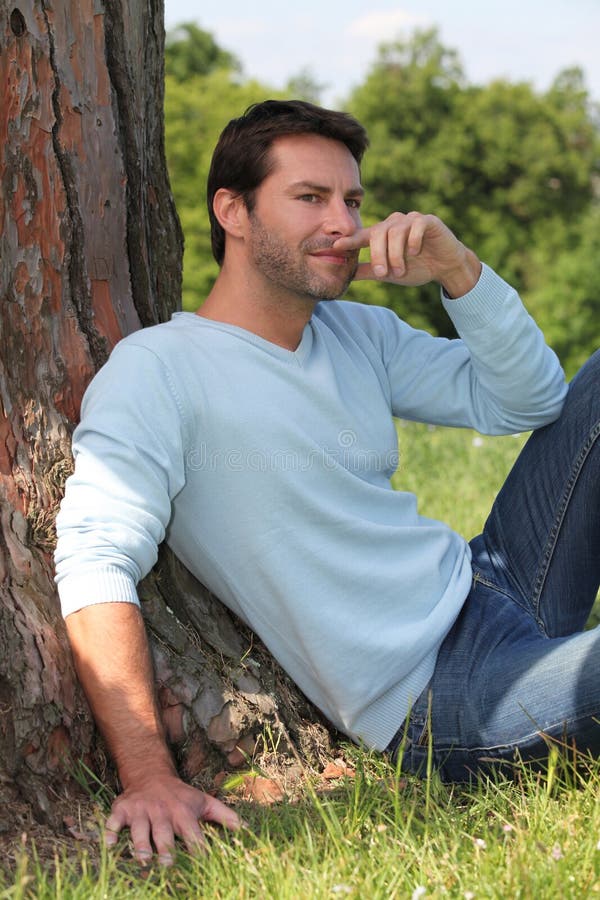 Man sitting against tree stock photo. Image of relaxed - 21963692
