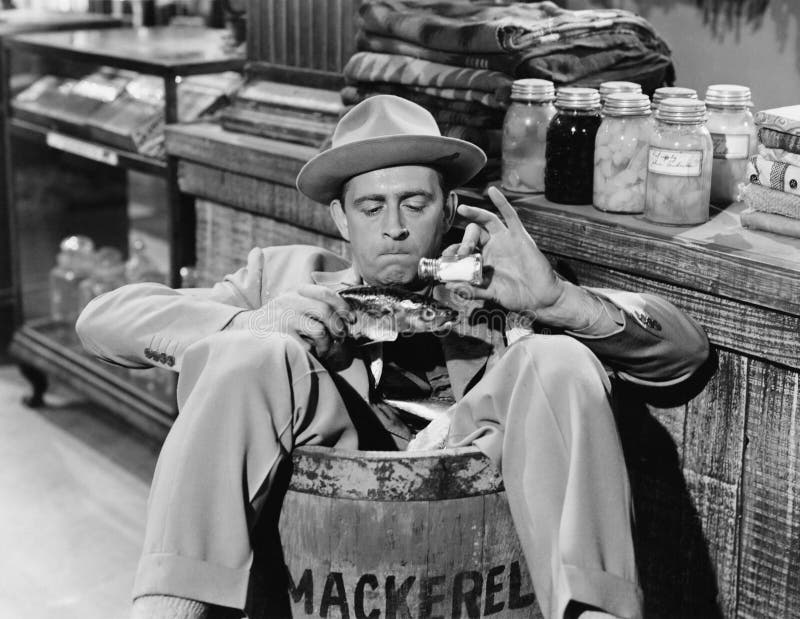 Man Sitting in a Barrel and Pouring Salt on a Fish Stock Photo - Image ...