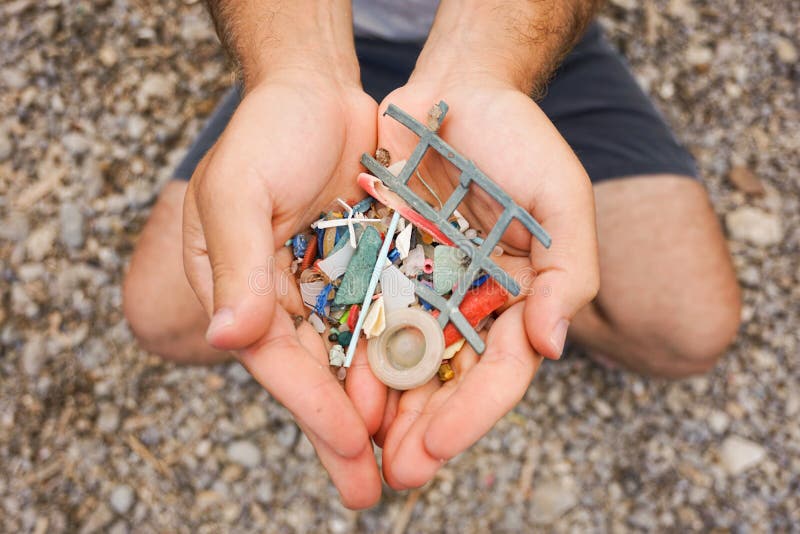 Man Sitting on the Beach and Holding with His Two Hands Plastic and ...