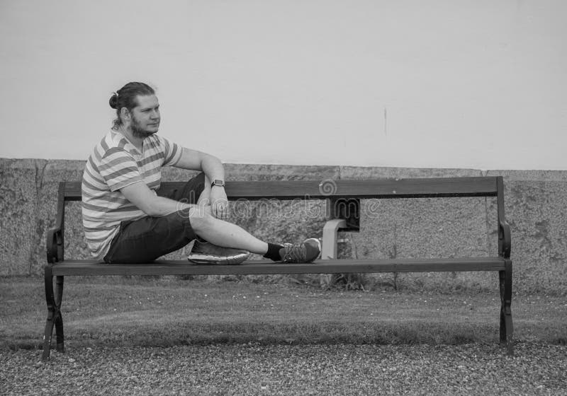 A Man Sitting on a Bench in Front of a Building Stock Photo - Image of ...