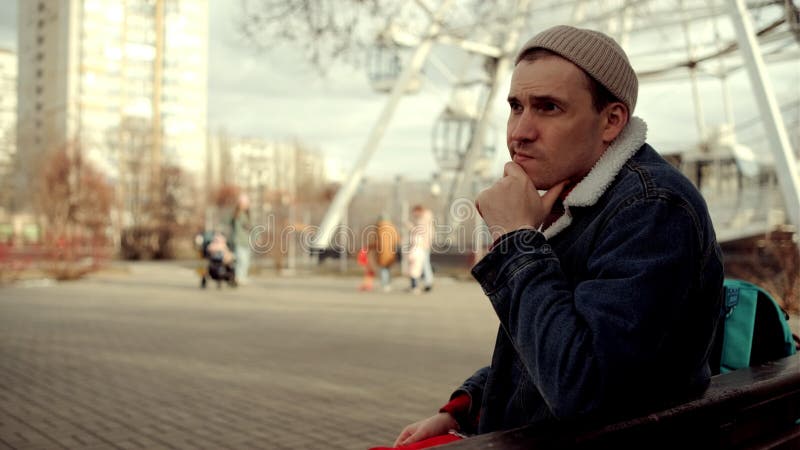 Man Sitting on Bench in Front of Ferris Wheel. a Man is Seated on a ...