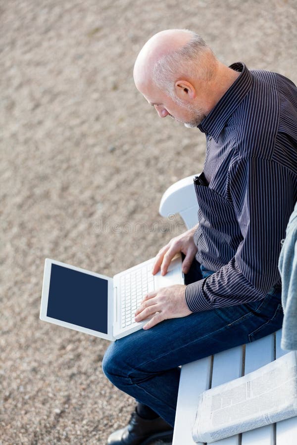 Man Sitting on a Bench Using a Laptop Stock Photo - Image of bench ...