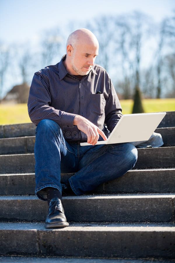 Man Sitting on a Bench Using a Laptop Stock Photo - Image of ...