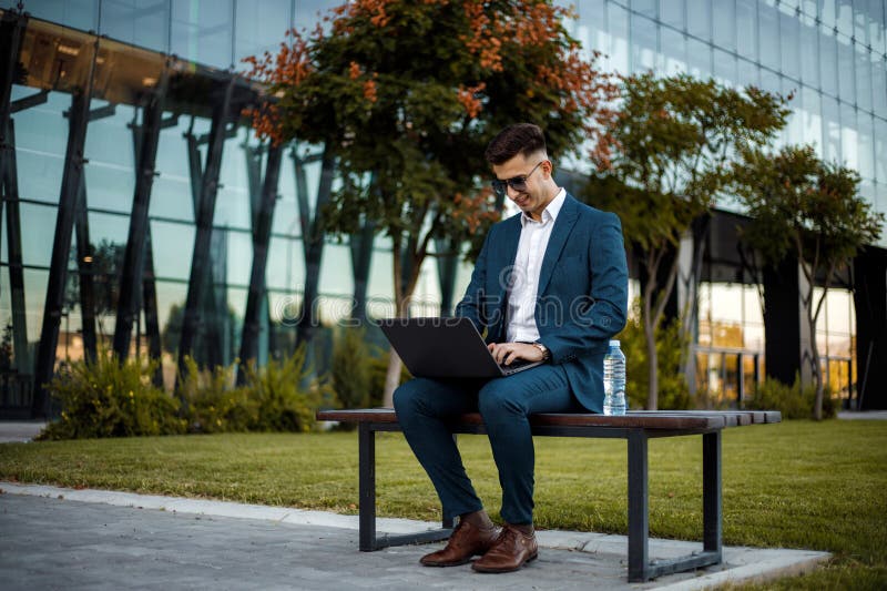 Man Sitting on Bench Using Laptop Stock Image - Image of street, modern ...