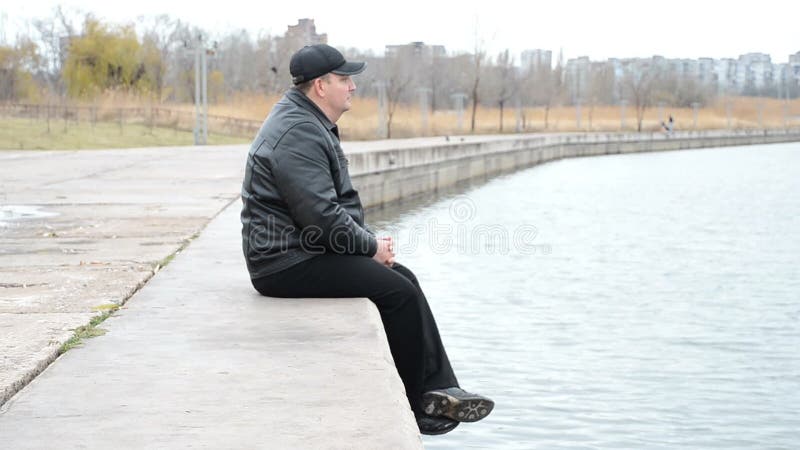 Man Sitting on Concrete Slabs Stock Footage - Video of beach, cold ...