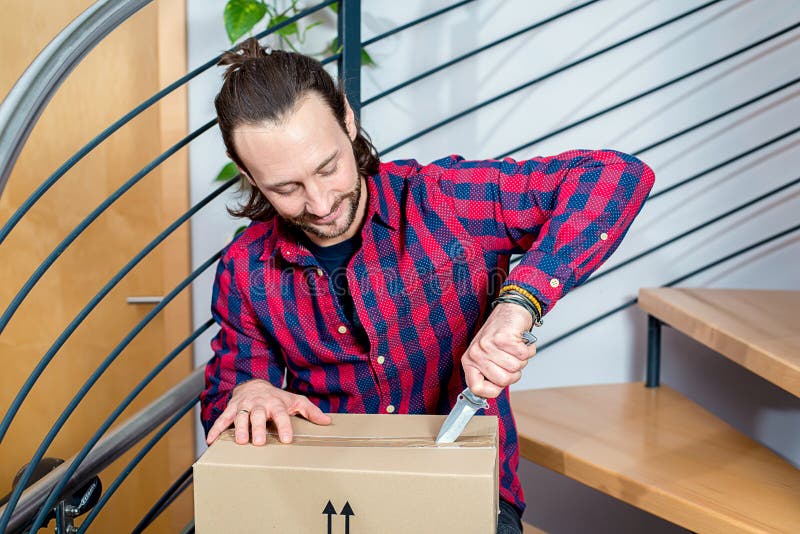 Man Sitting in Corridor and Opening a Package Stock Photo - Image of ...