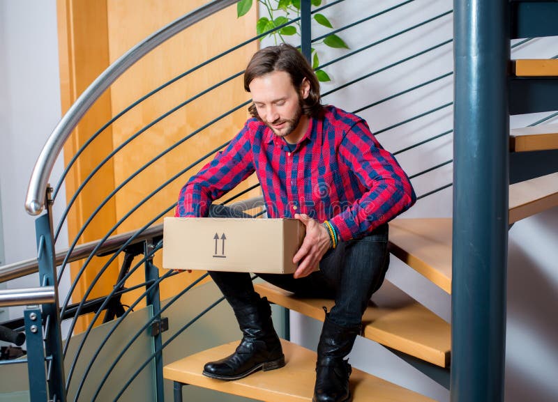 Man Sitting in Corridor and Opening a Package Stock Photo - Image of ...