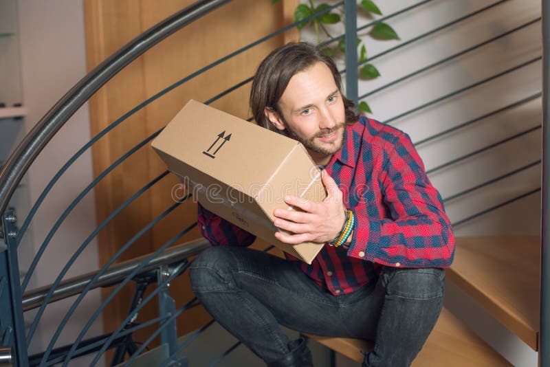 Man Sitting in Corridor and Opening a Package Stock Photo - Image of ...
