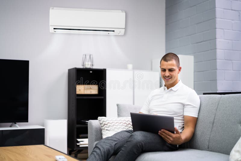 Man Sitting on Couch with Air Conditioner Stock Photo - Image of ...