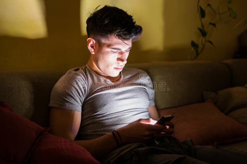 Man Sitting on Couch Looking at Cell Phone Stock Image - Image of ...