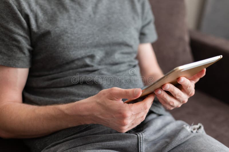 Man Sitting on a Couch and Reading Something on a Tablet. Using ...